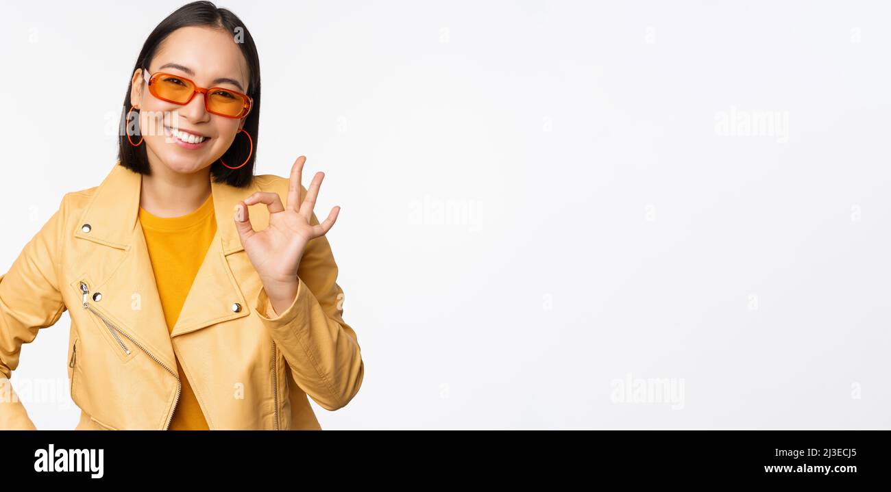 Excellent. Smiling asian girl shows okay, ok sign, nod in approval ...