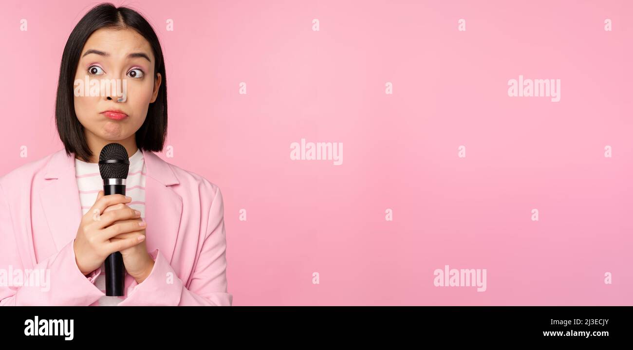 Nervous female entrepreneur giving speech with microphone, holding mic ...