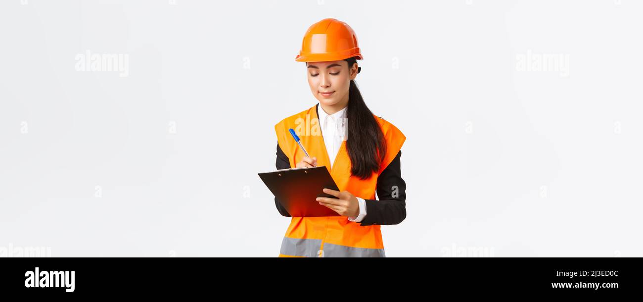 Pleased asian female construction engineer, architect taking notes in ...