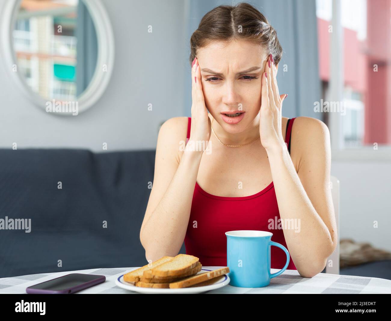 Upset woman crying while sitting at the table in room Stock Photo - Alamy