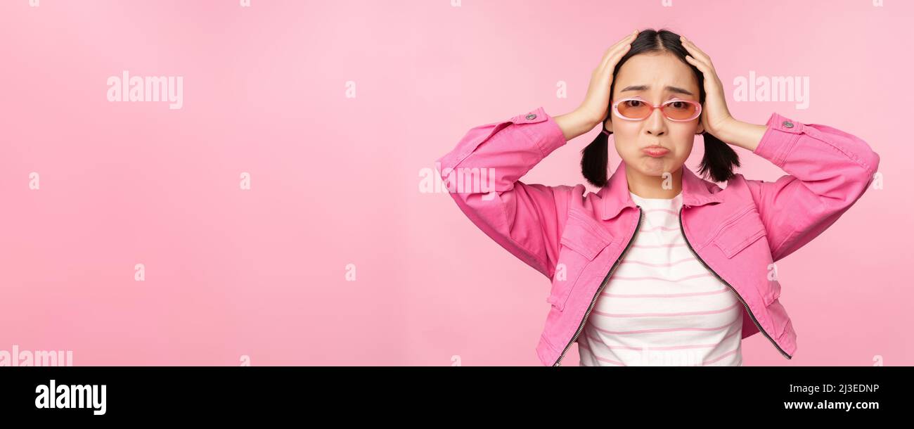 Portrait of troubled asian woman, korean girl holds hands on head and ...