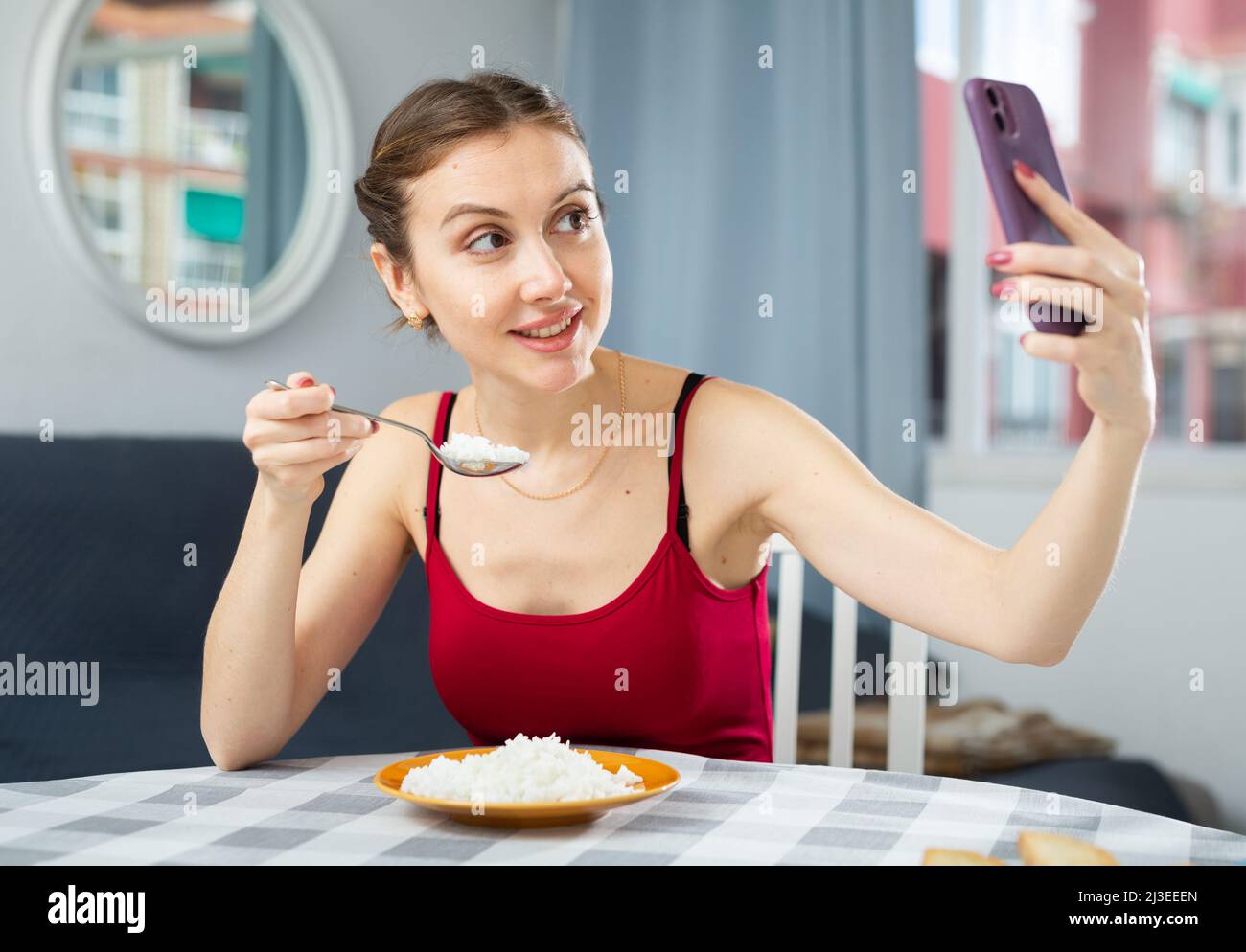 Positive woman eating rice at home and taking selfies Stock Photo - Alamy