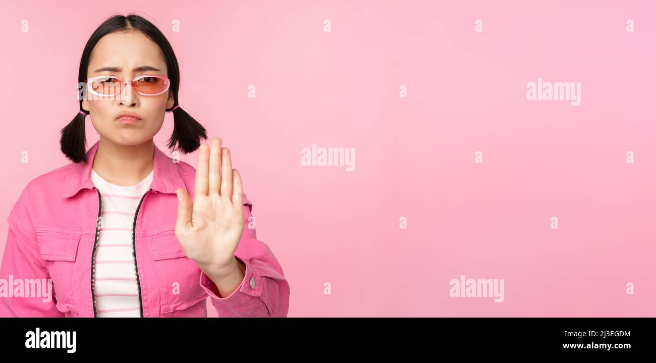 Image of serious, stylish asian girl in sunglasses, showing stop ...