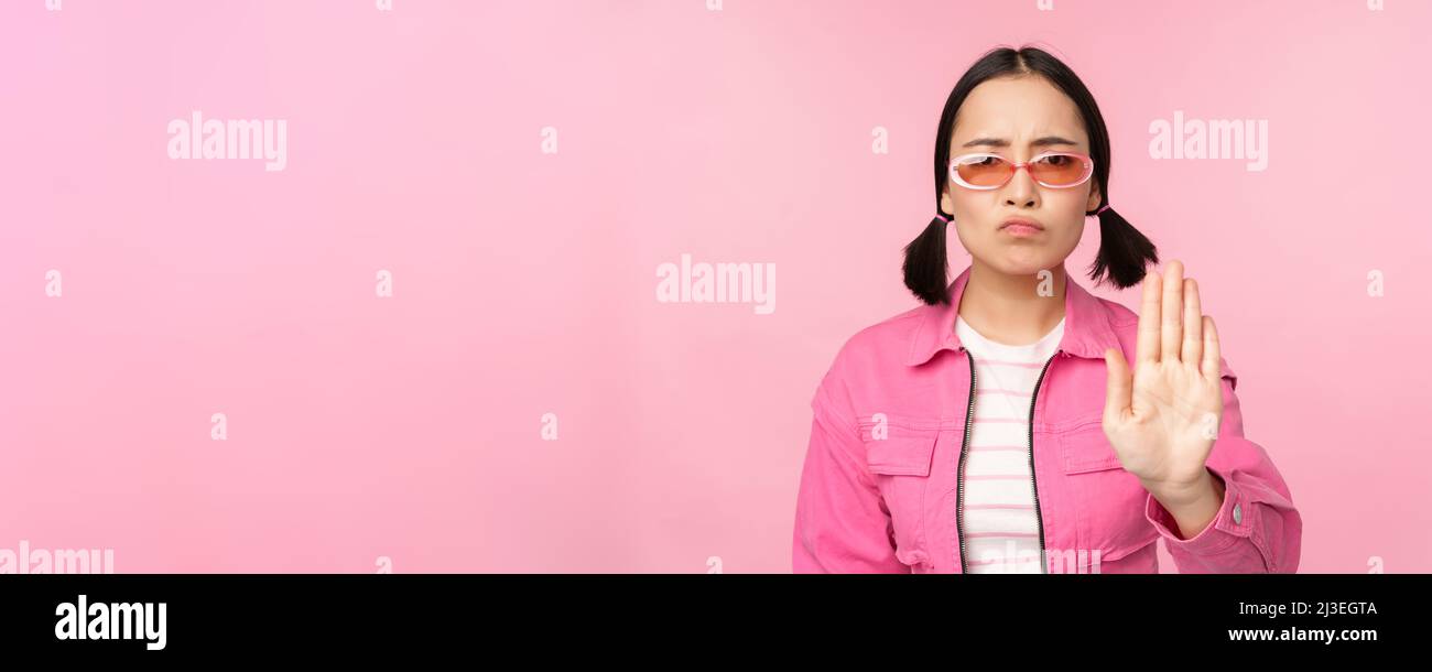 Image of serious, stylish asian girl in sunglasses, showing stop ...