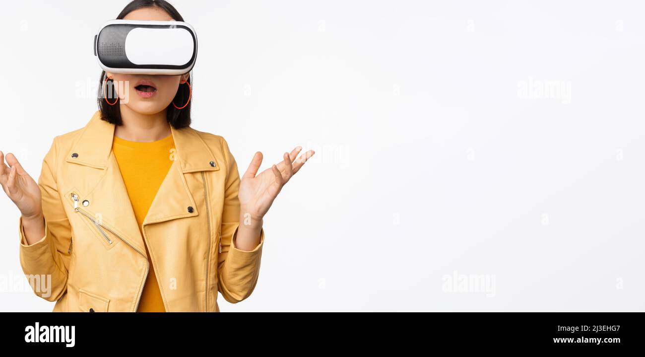Young asian girl wearing VR glasses, looking amazed, using virtual ...
