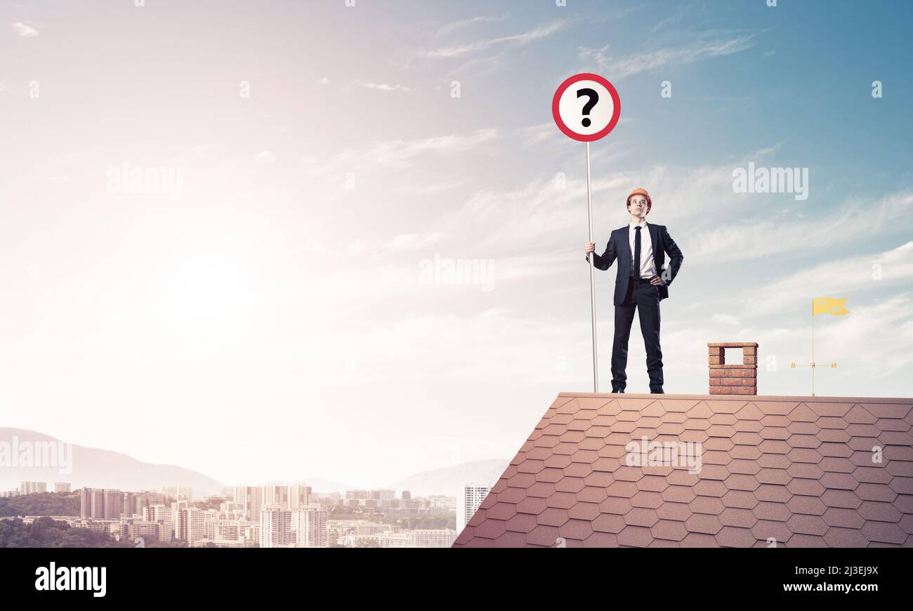 Businessman on brick house roof showing banner with question mar Stock ...