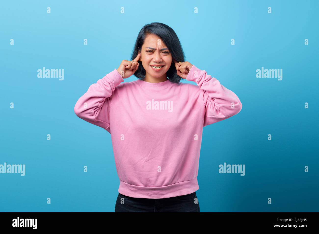 Portrait of angry young woman covering her ears, stop making that loud ...