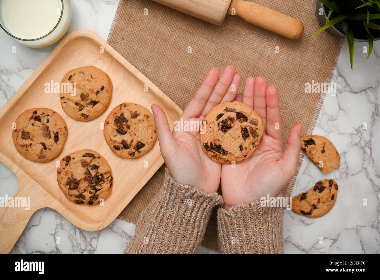 Top view, A chocolate chip cookie in a woman hands over pastries baking ...