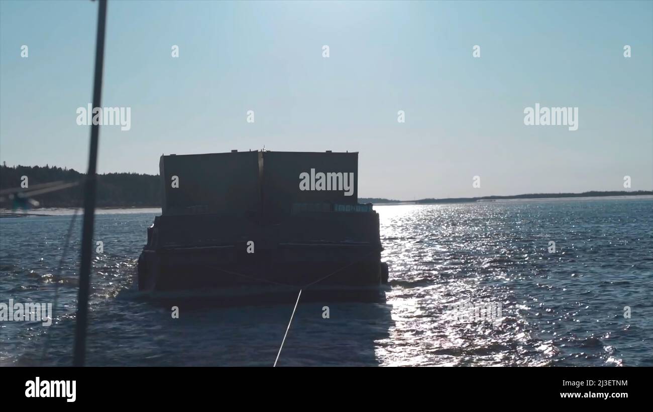 View of floating barge behind ship. Clip. Trading barge floats on river ...