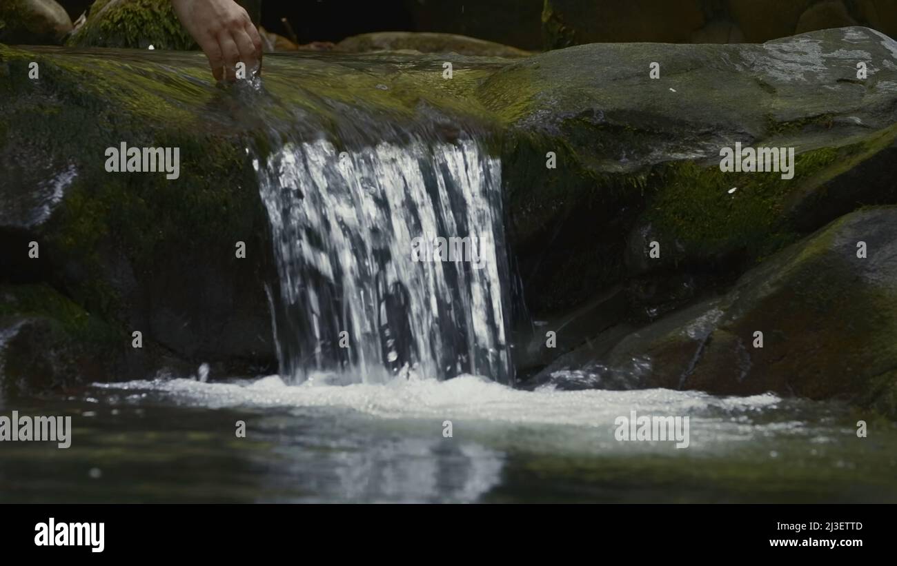 Hand in small river waterfall. Creative. Man of refreshing river ...
