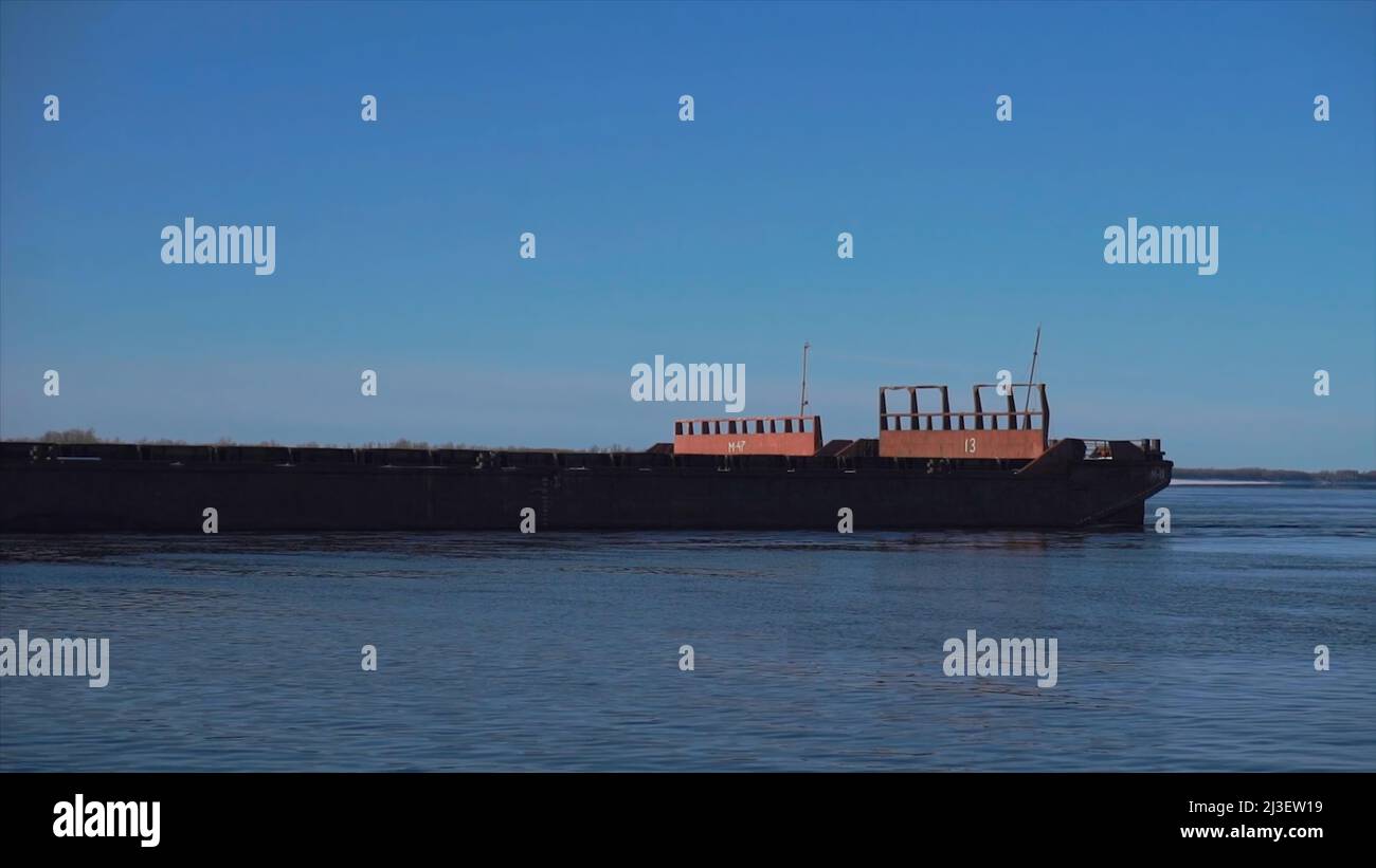 Cargo ship sailing on river on clear day. Clip. Merchant ship or barge ...