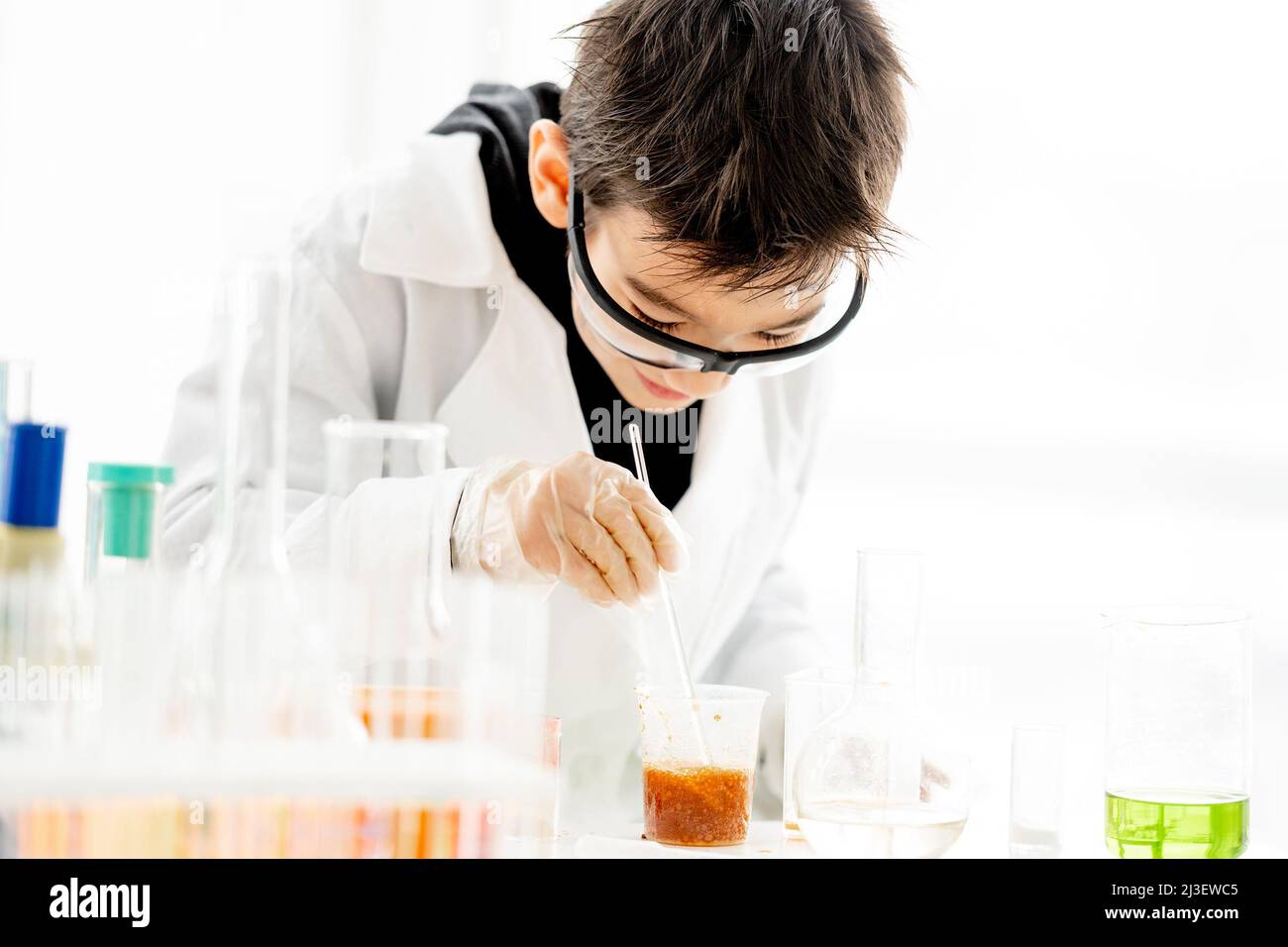 School boy wearing protection glasses doing chemistry experiment in ...