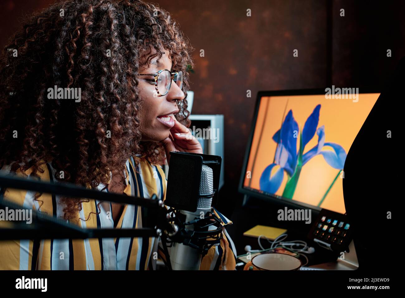 young afro american artist podcasting with a microphone in front of her ...