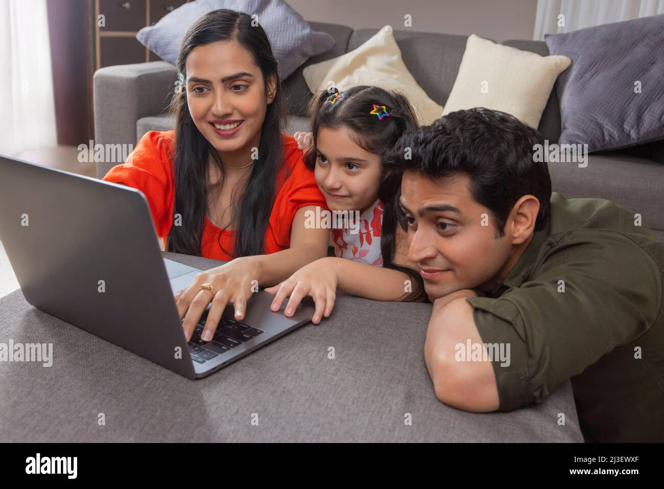 Parent using laptop with their girl child at home Stock Photo - Alamy