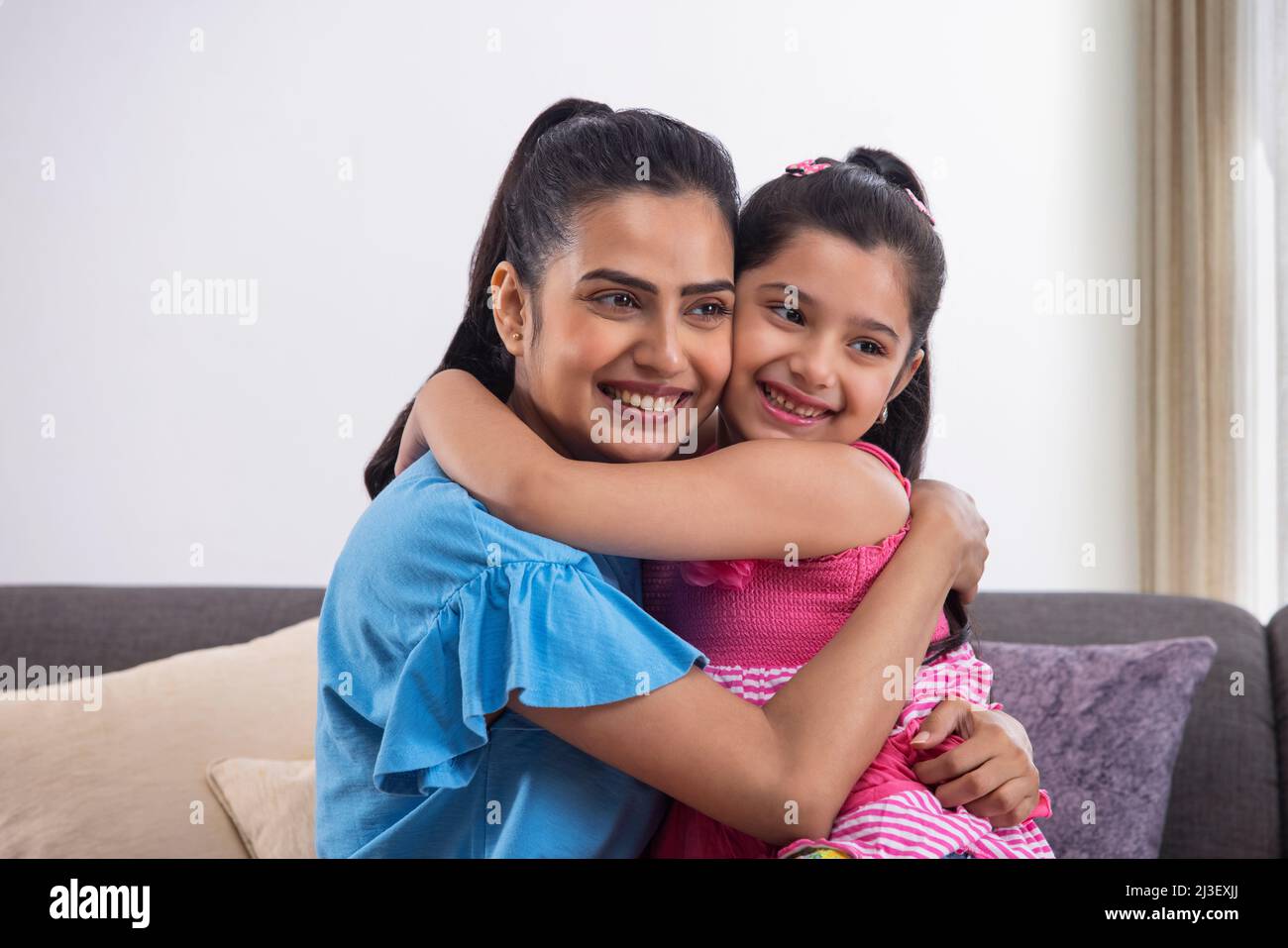 Mother and daughter hugging each other at home Stock Photo - Alamy