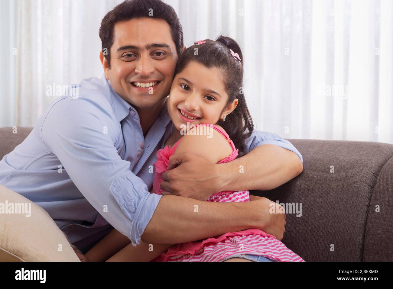 Father hugging his daughter on sofa at home Stock Photo - Alamy