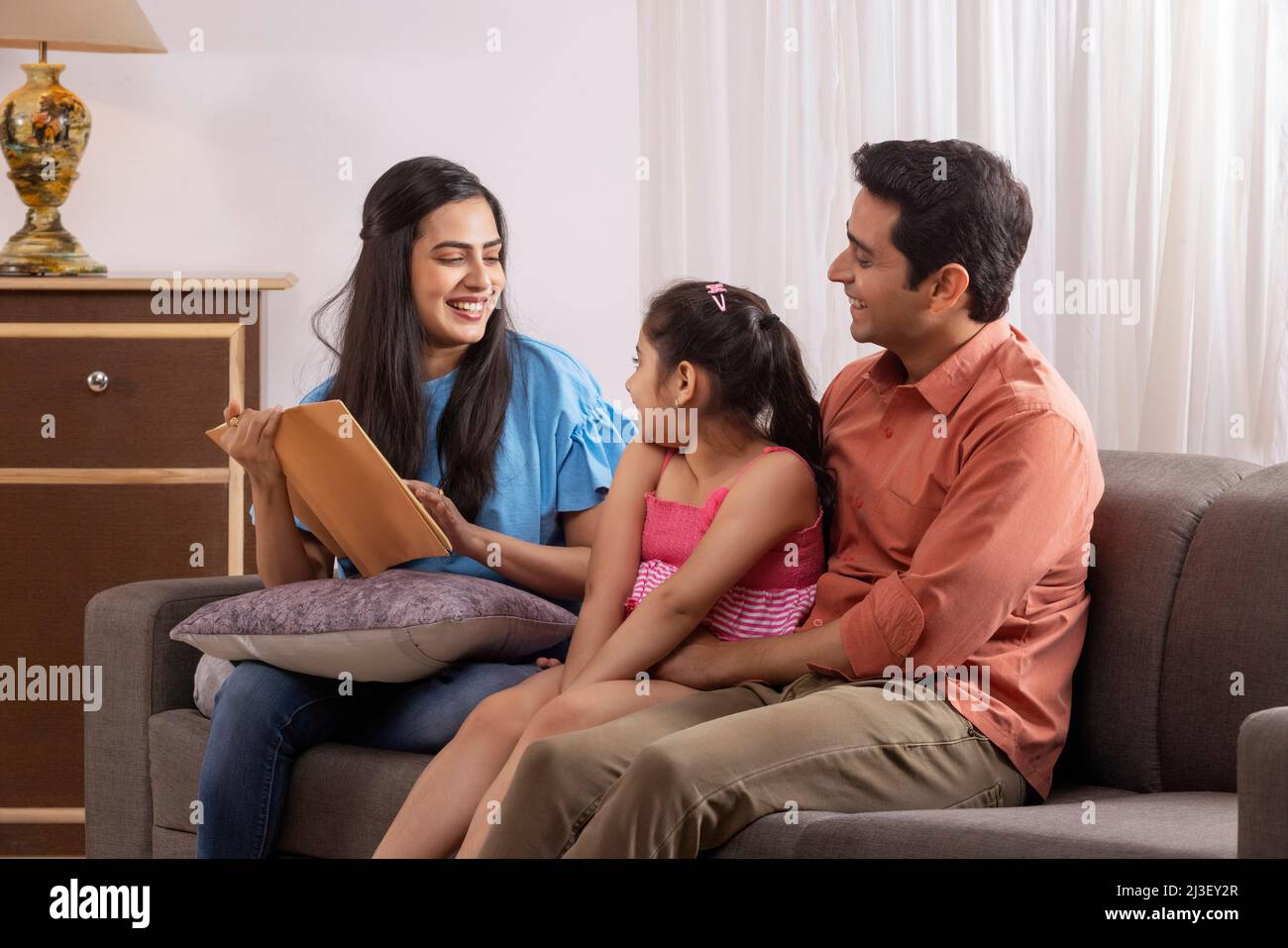 Family members talking with each other while sitting on sofa at home ...