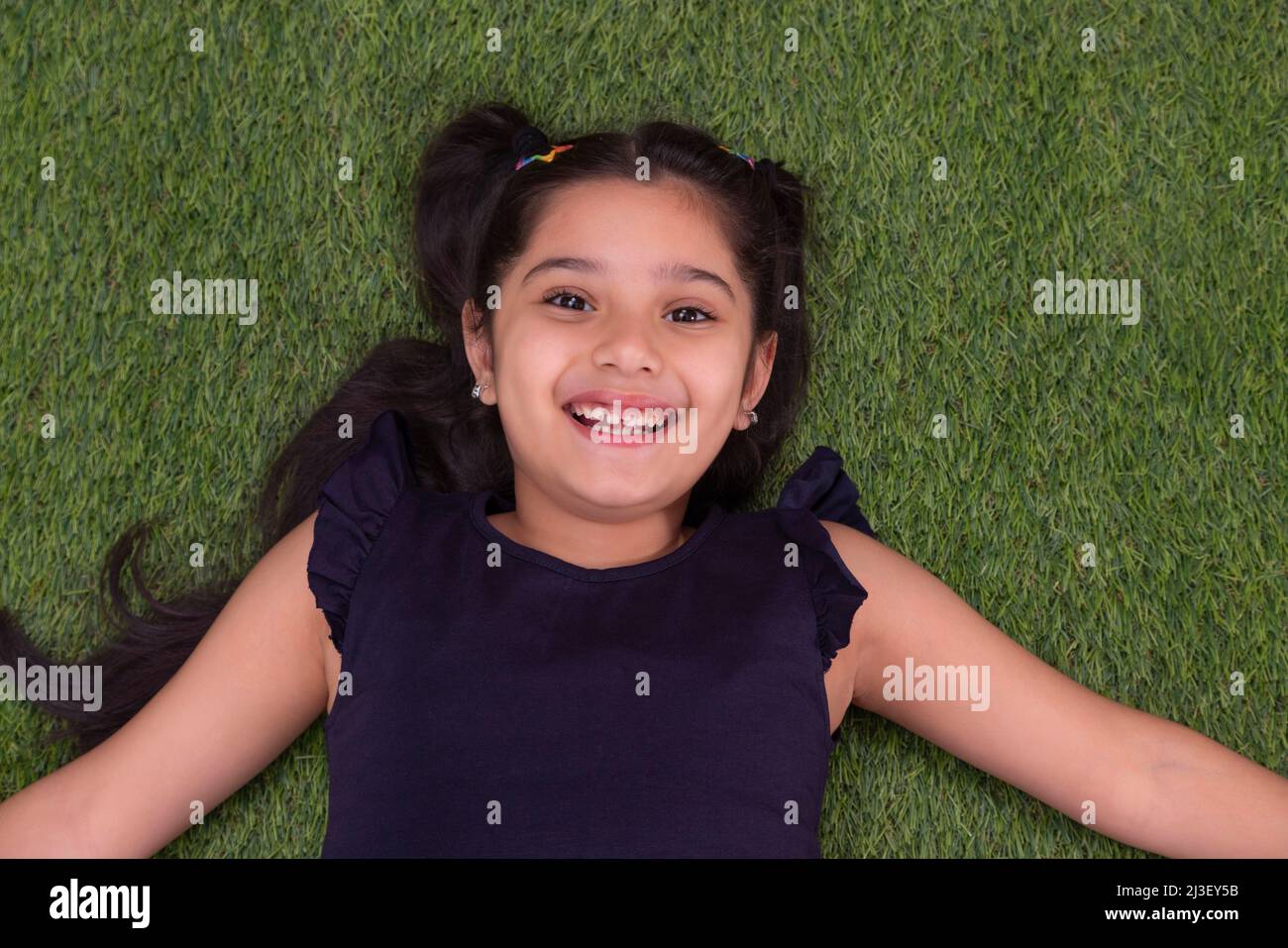 Overhead view of girl child lying on grass Stock Photo - Alamy
