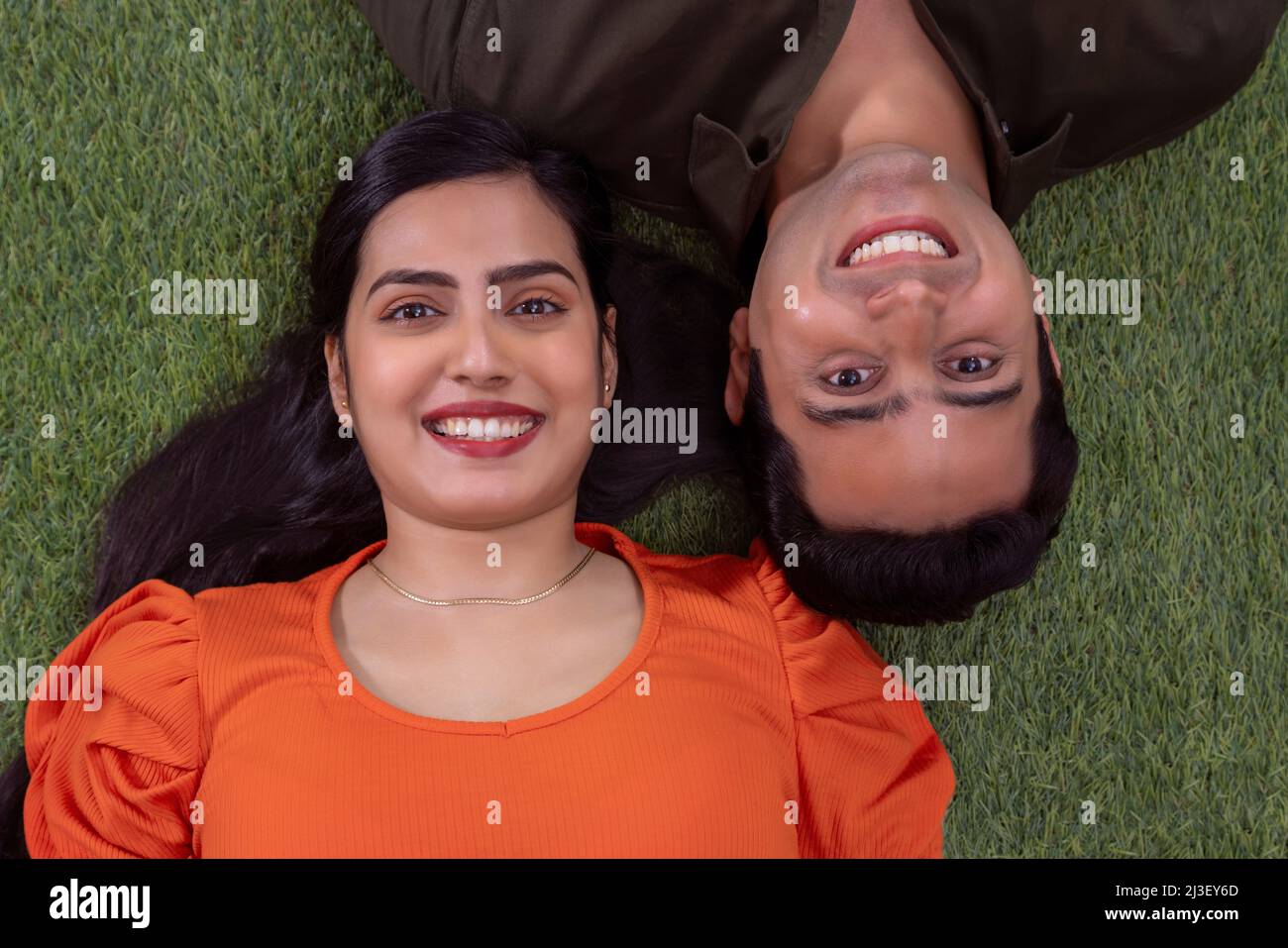 Overhead view of young couple lying on grass Stock Photo - Alamy