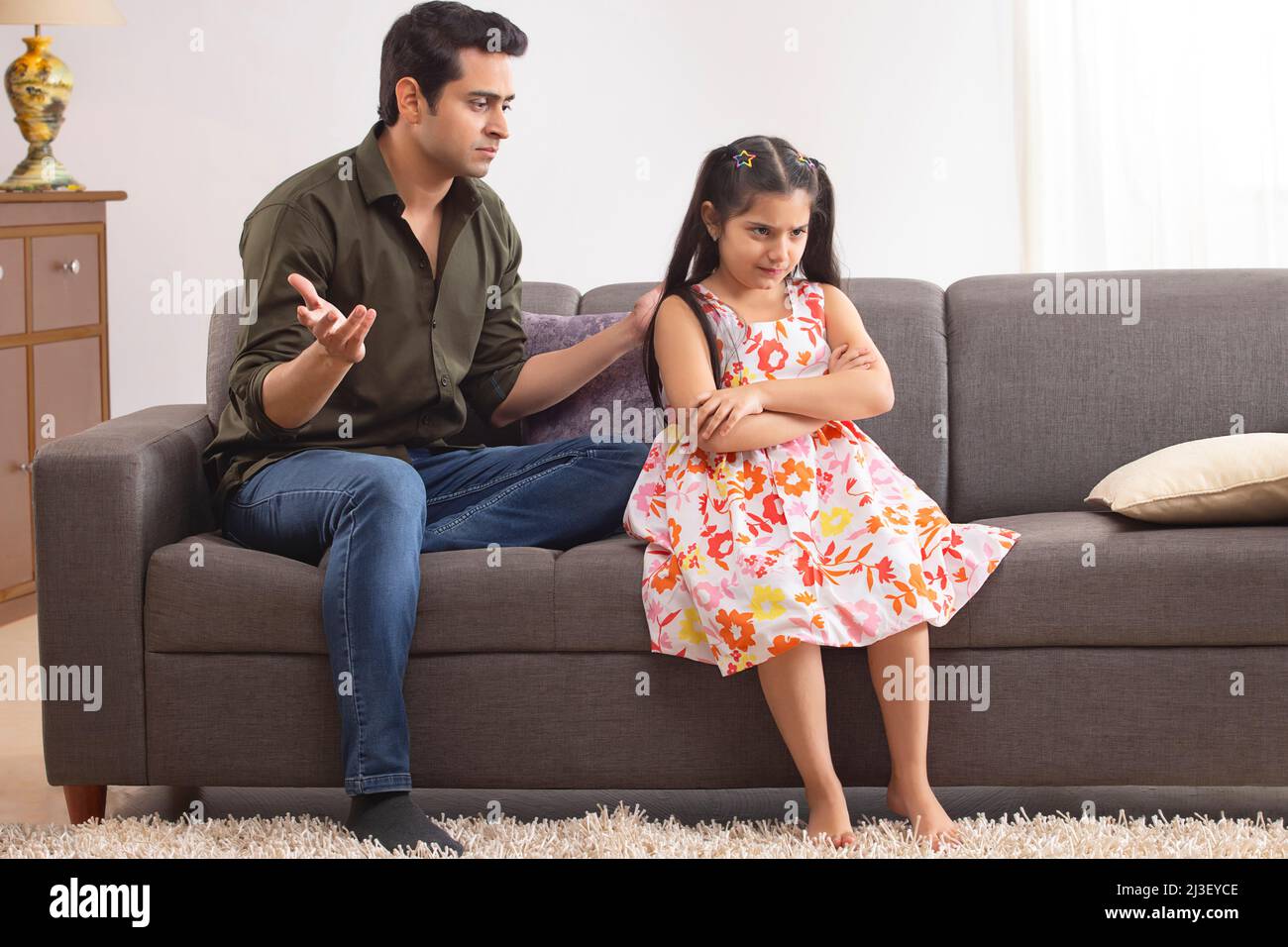 Father trying to control his daughter's anger while sitting on sofa ...