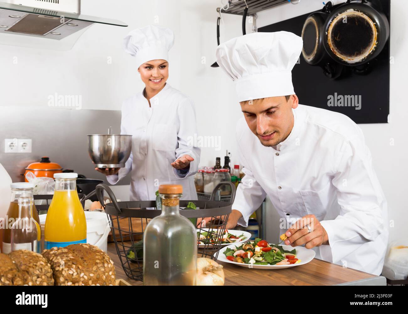 Two happy female and male young cooks Stock Photo - Alamy