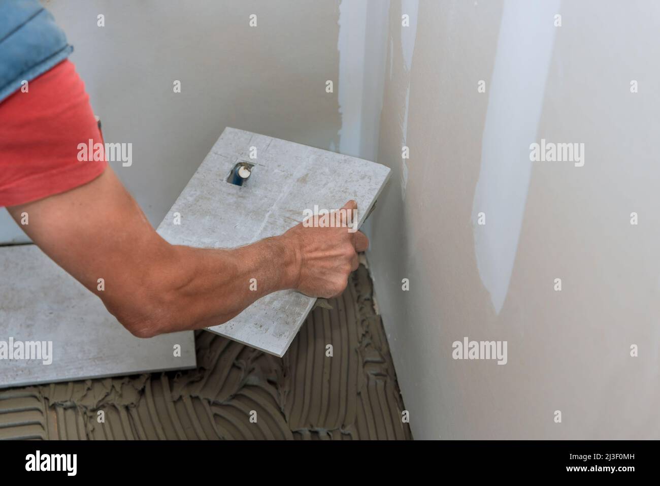 Workers hands with applying tile adhesive to the floor process of ...