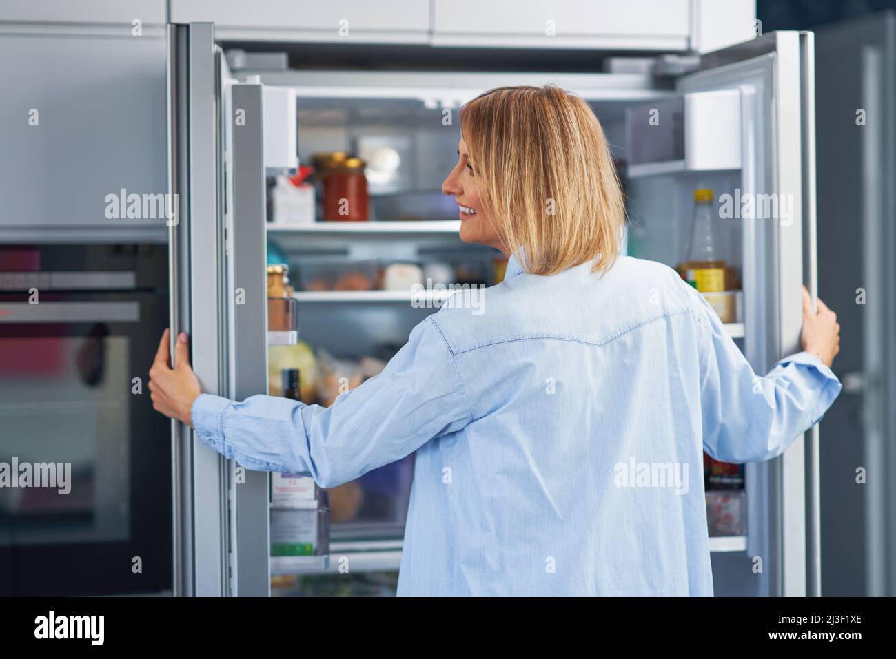 Young adult woman in the kitchen with the fridge Stock Photo - Alamy