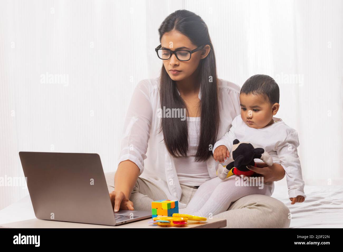 Mother holding child in her lap while using laptop Stock Photo - Alamy