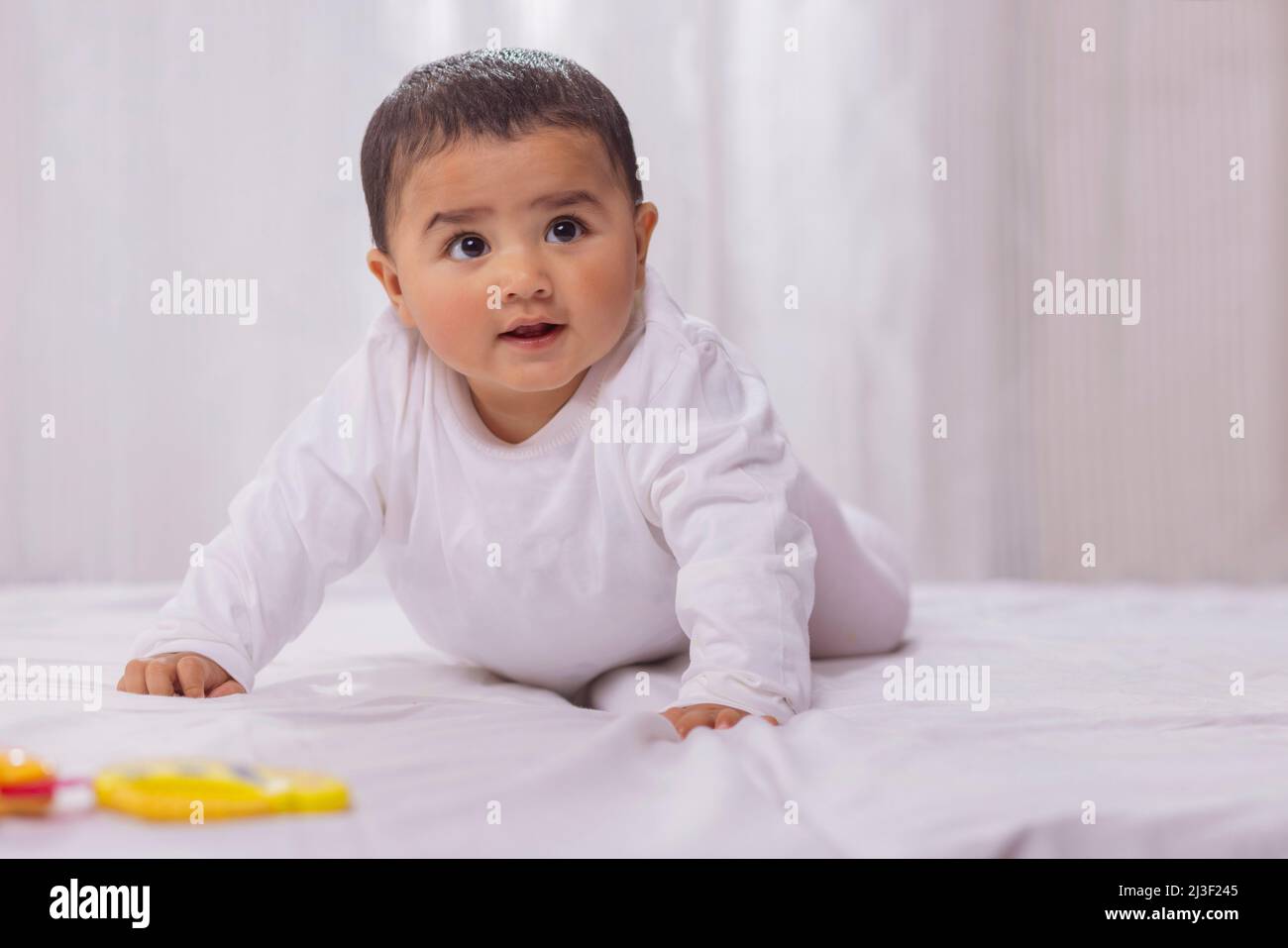 Cute little child crawling on bed alone Stock Photo - Alamy