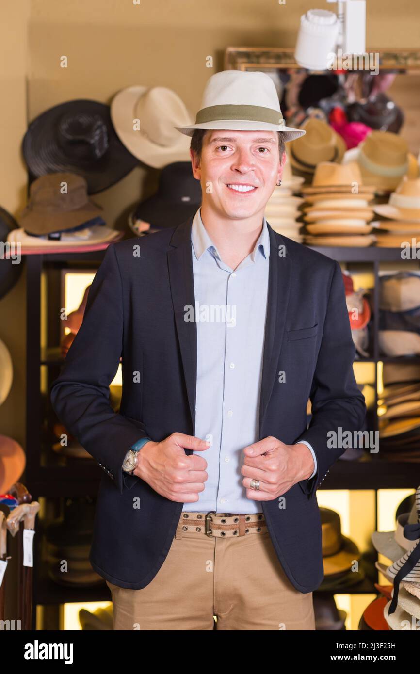portrait of positive male try on cap at the shopping mall Stock Photo ...