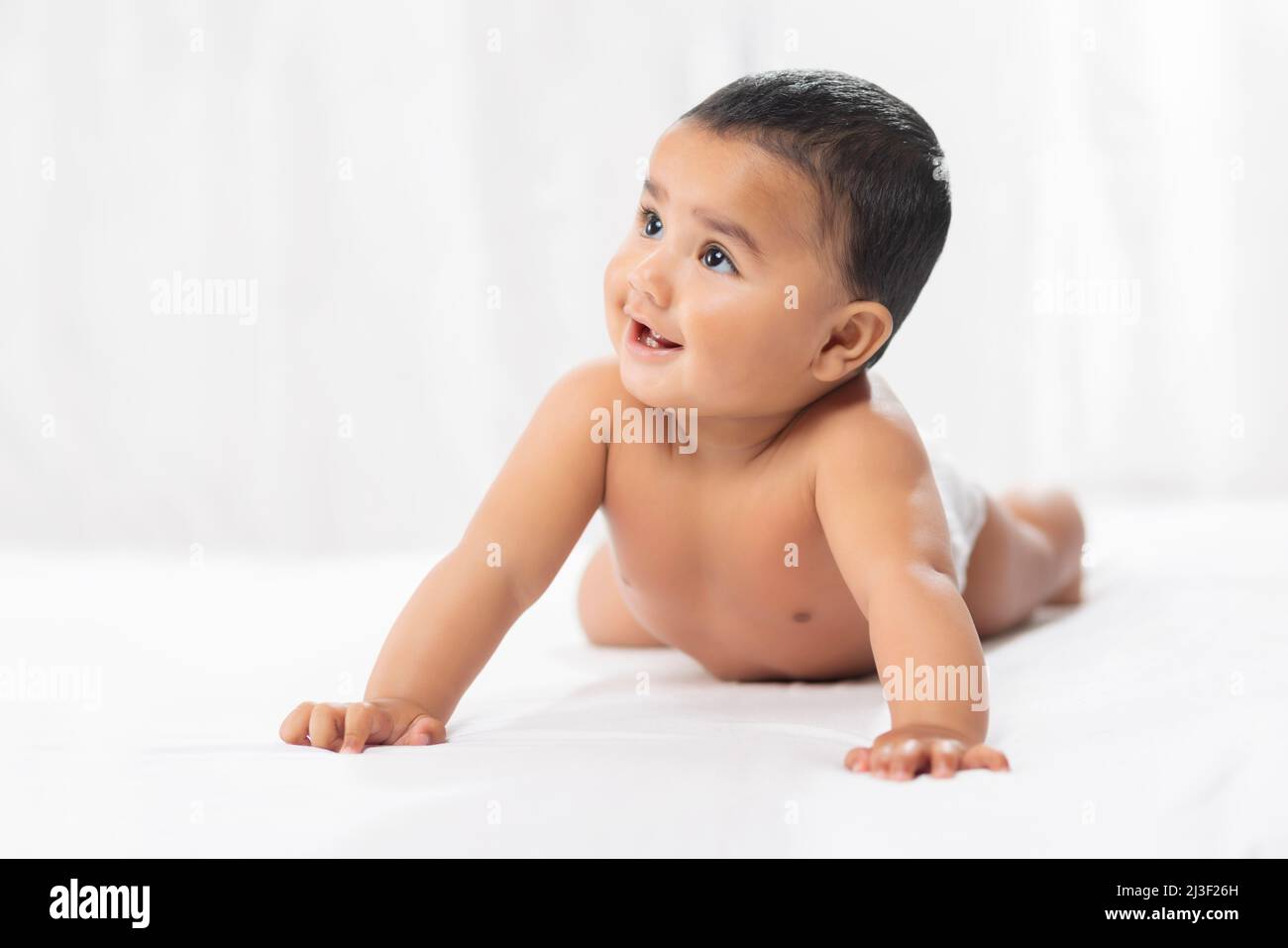 Cute baby in diaper crawling on bed Stock Photo - Alamy