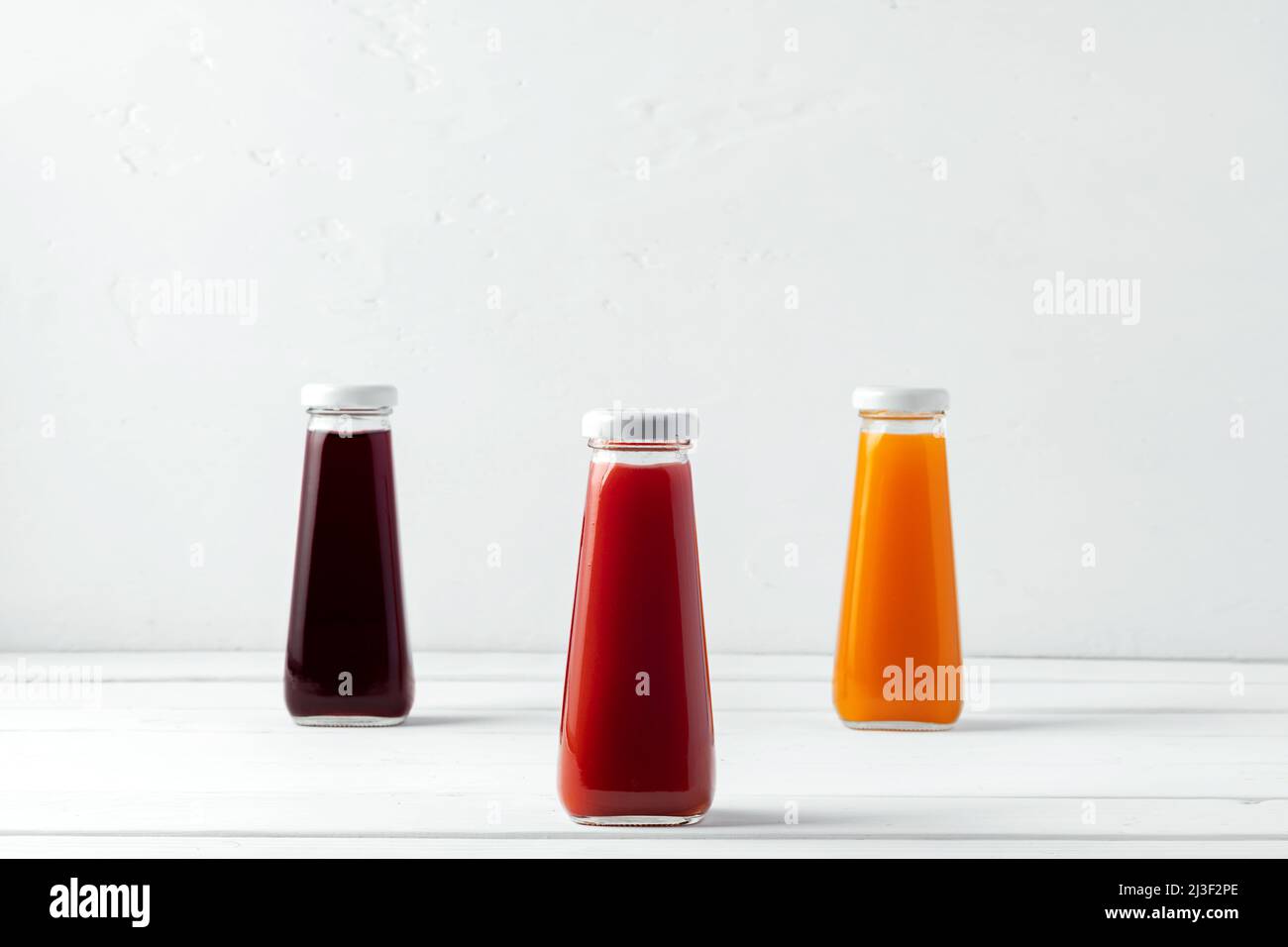 Glass bottles of different juices on white background Stock Photo - Alamy