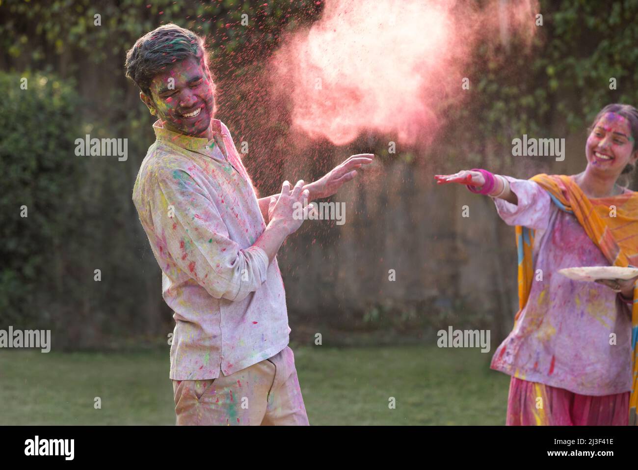 Young woman celebrating Holi by throwing dry colour at her husband ...