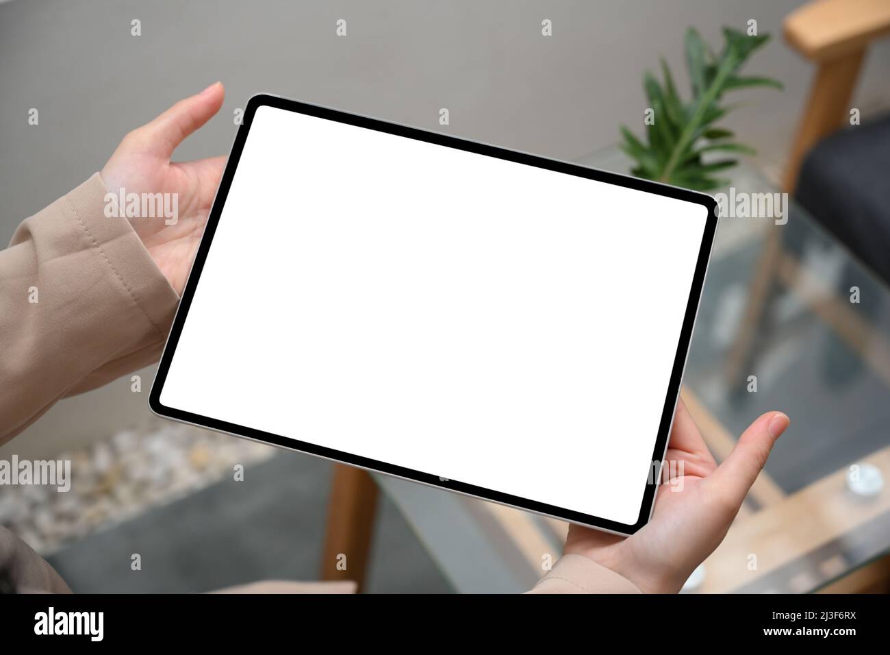 Digital tablet white screen mockup in a woman hand over blurred minimal ...