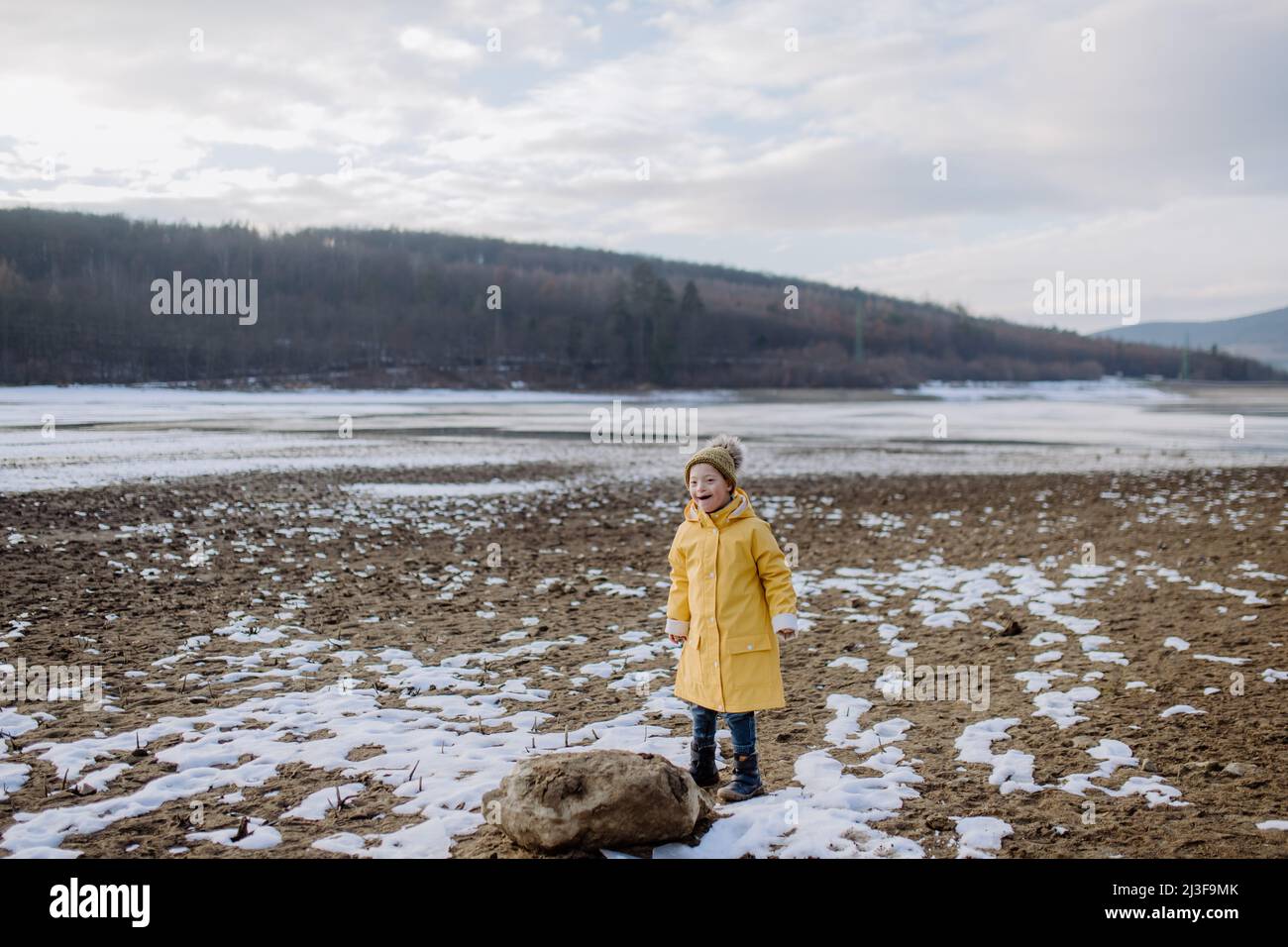 Sad little boy with Down running outside by lake in winter Stock Photo ...