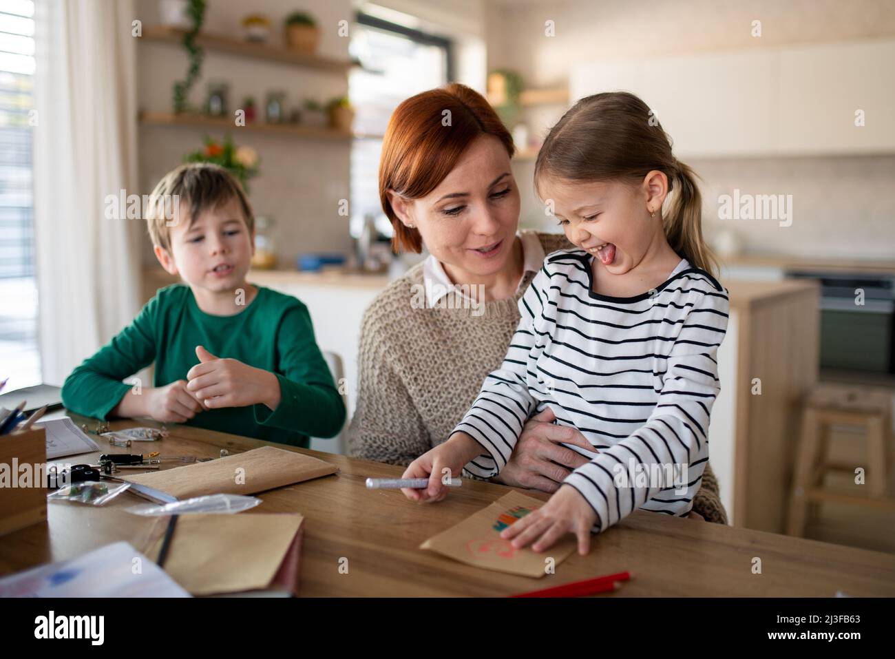 Mother of little children supervising them when diong homework at home ...