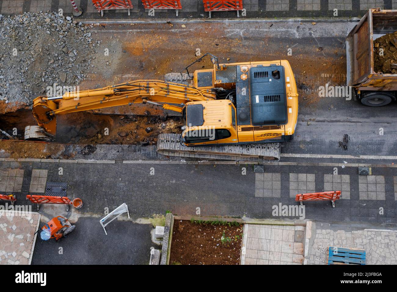 construction equipment excavates a city street to improve the ...