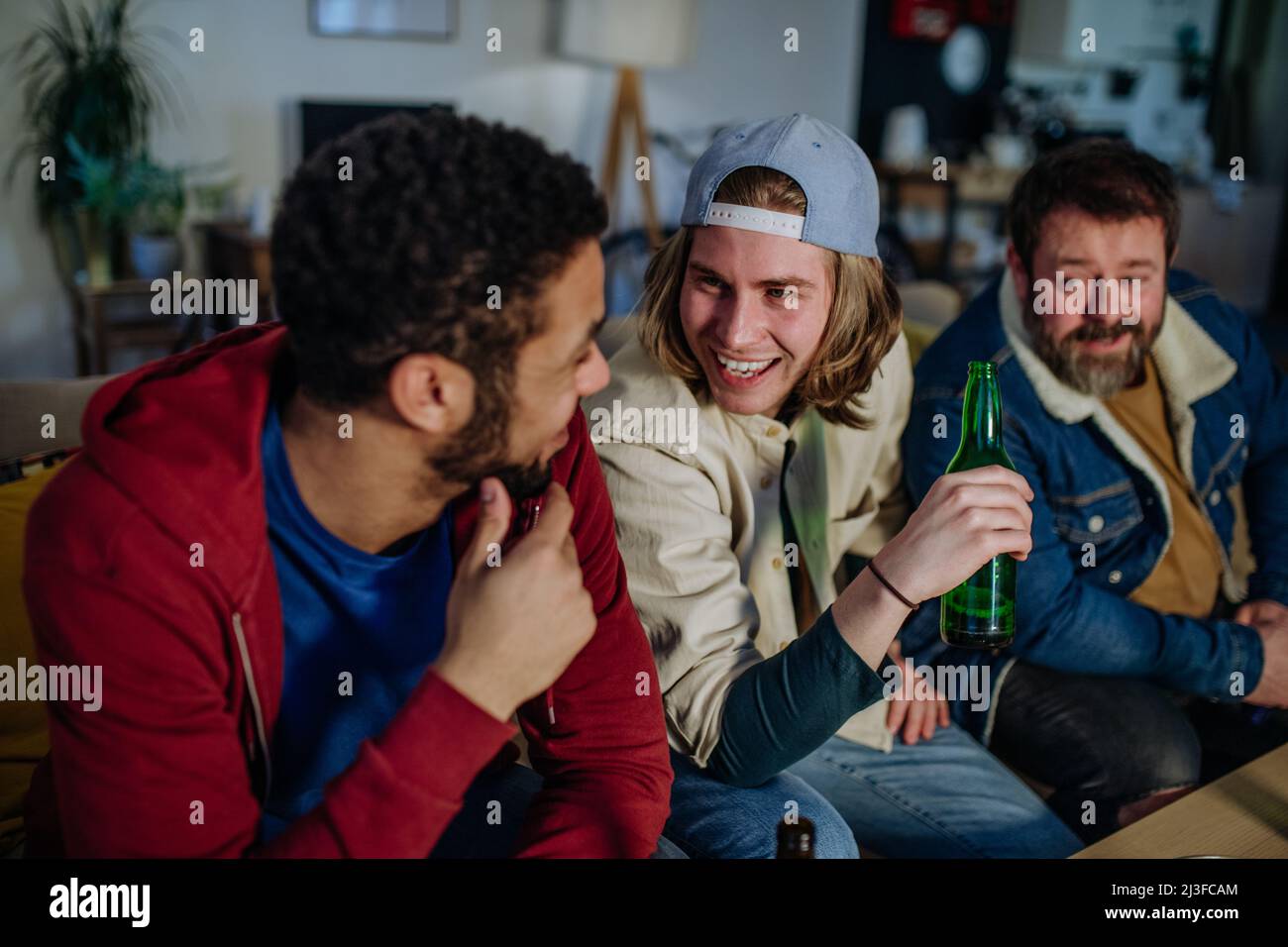 Happy football fans friends watching football at home and talking Stock ...