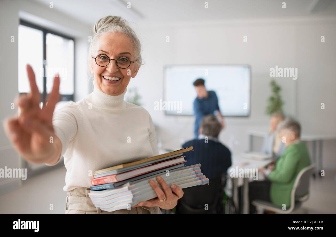 Happy senior woman student with books raising hand and looking at ...