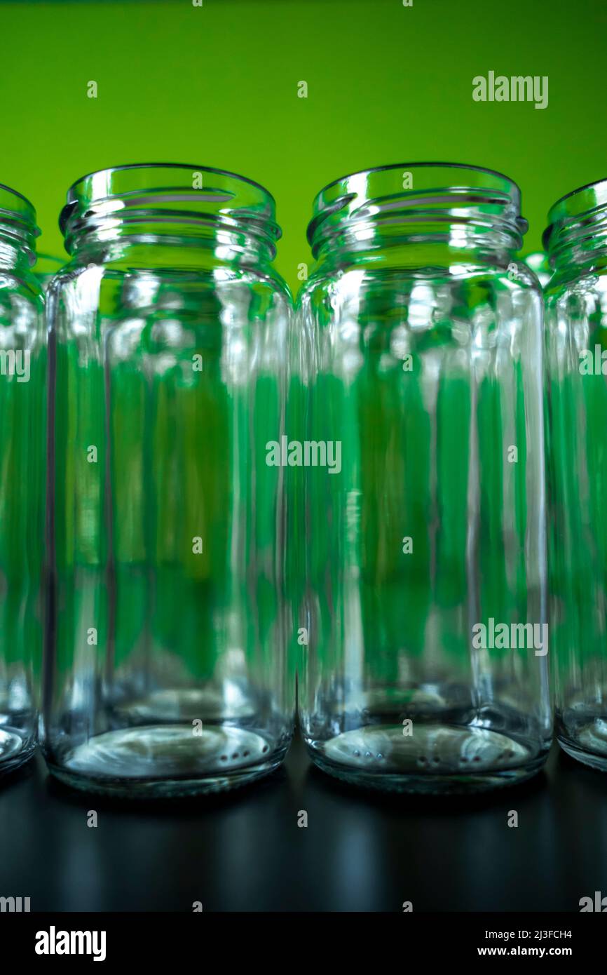 Frontal shot of empty glass jars lined up in a row on a green ...
