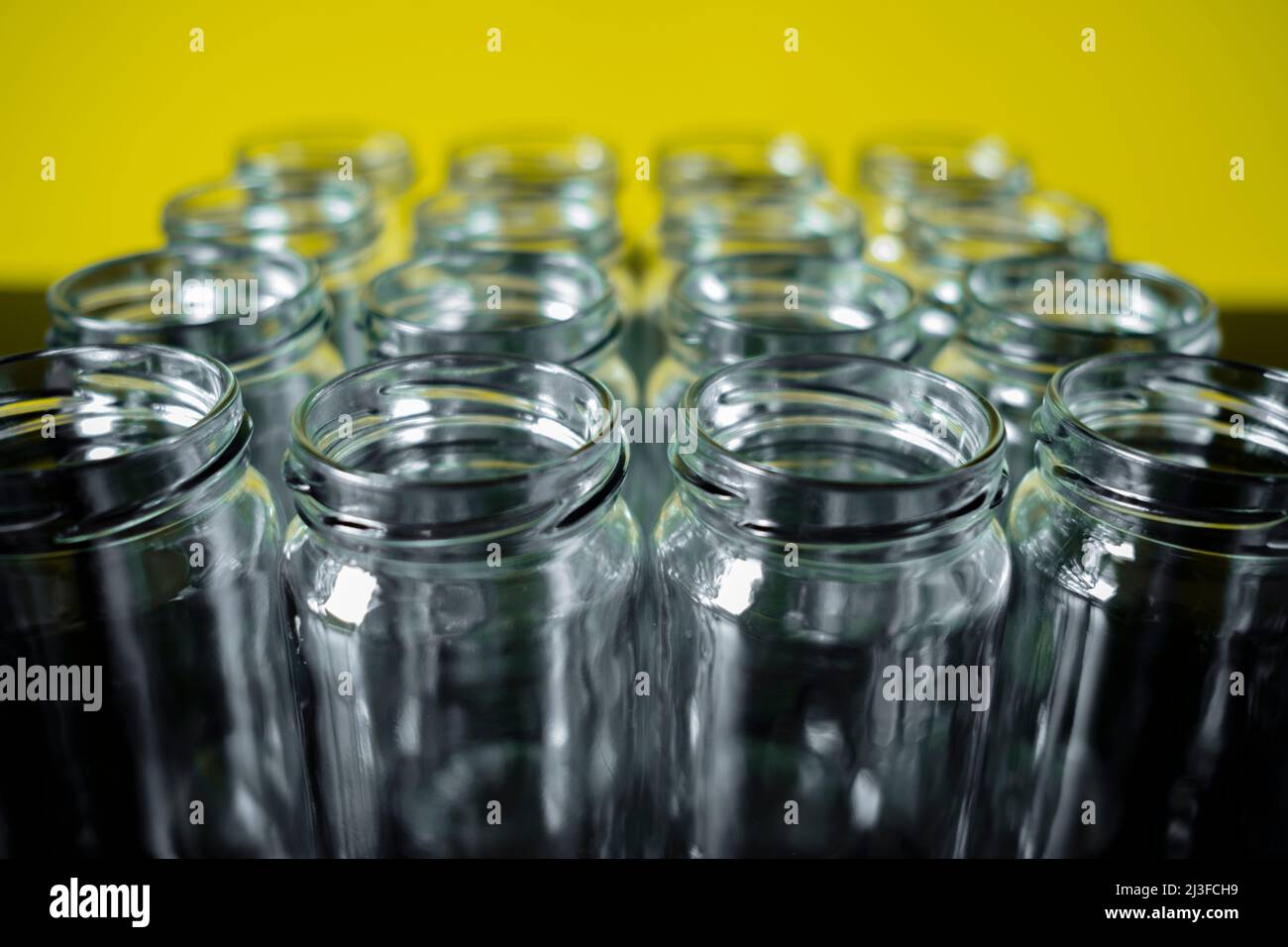 Frontal shot of empty glass jars lined up in a row on a gyellow ...