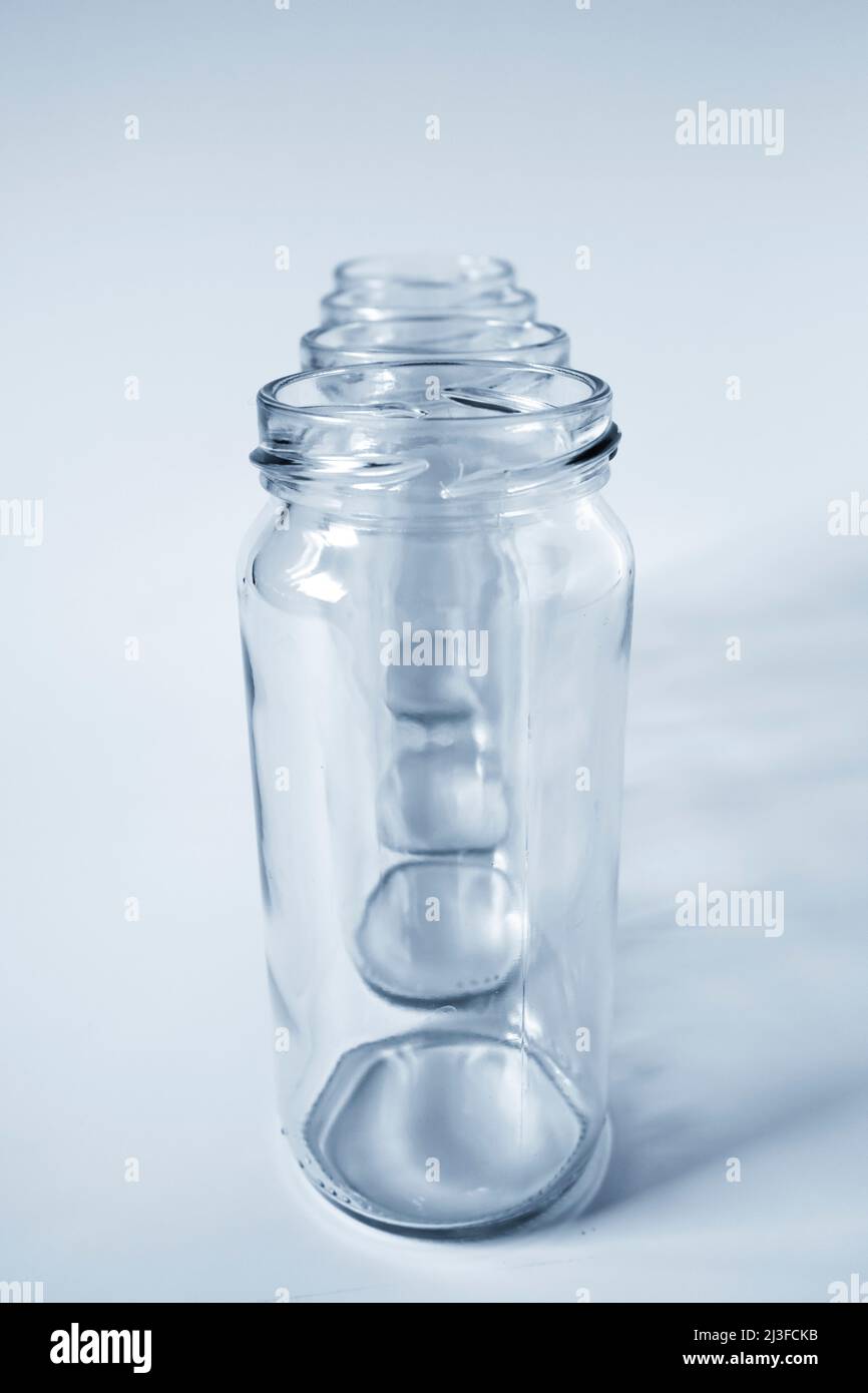Frontal shot of empty glass jars lined up in a row on a white ...