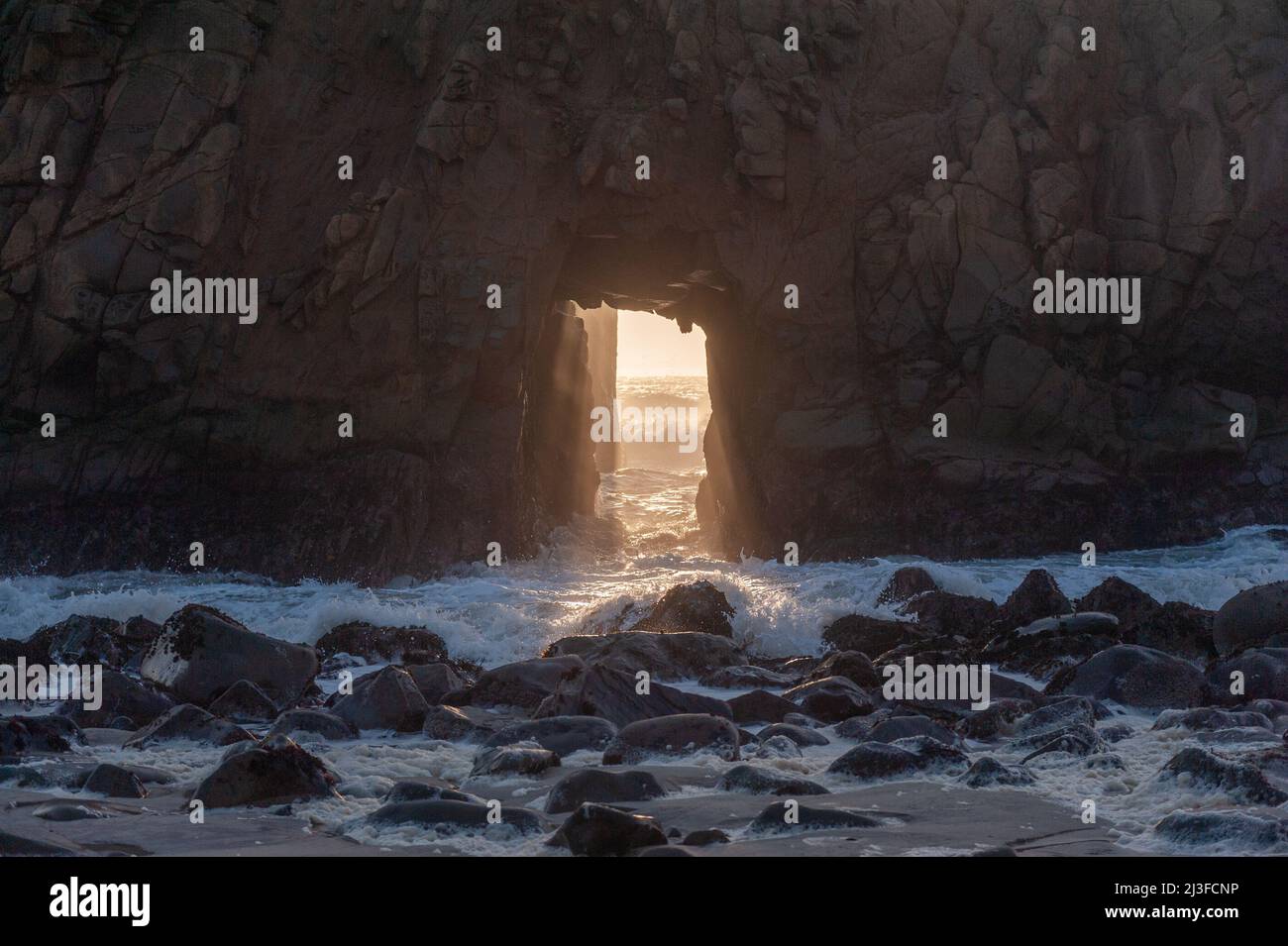 The setting sun is peaking through the keyhole arch at Pfeiffer Beach ...