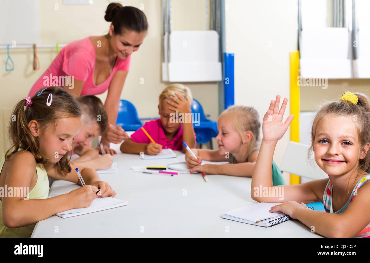 children making writing exercises with help of teacher in class Stock ...
