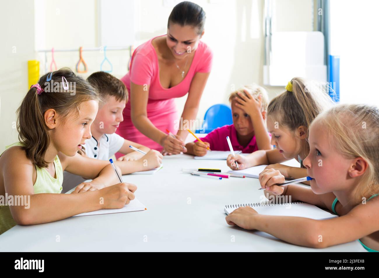 children making writing exercises with help of teacher in class Stock ...