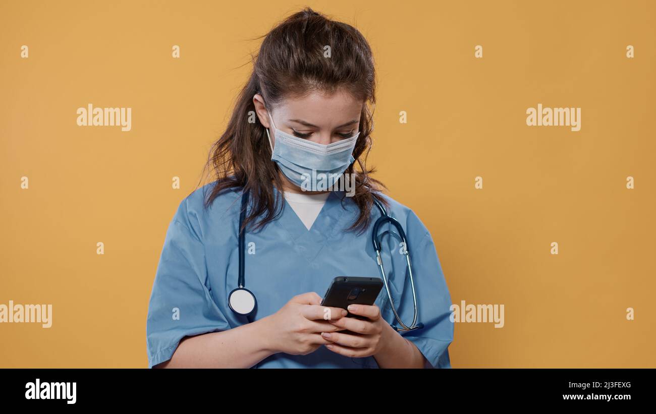 Portrait of doctor with stethoscope holding smartphone and texting ...