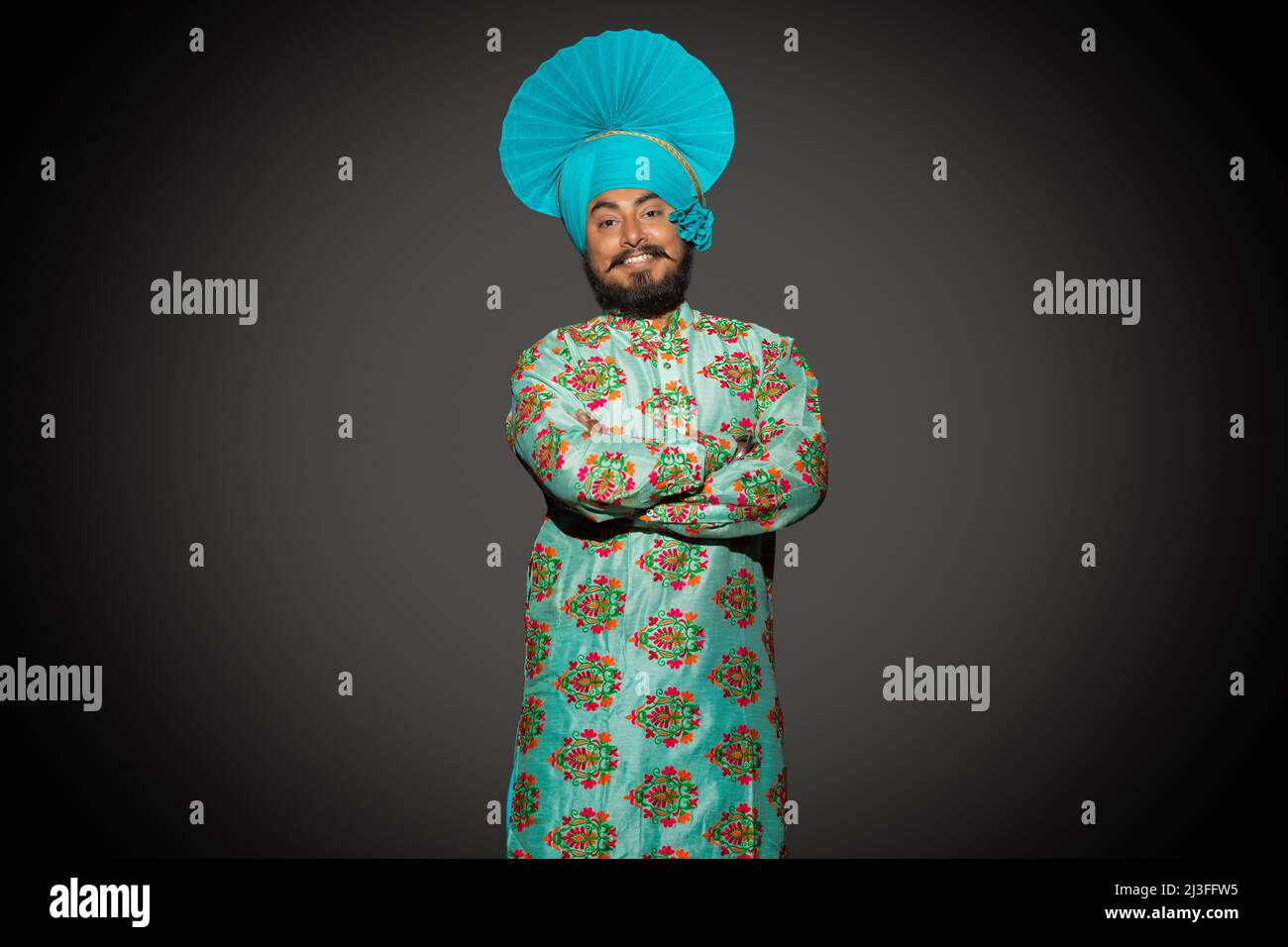 Portrait of a happy Sikh man posing in front of camera with arms ...