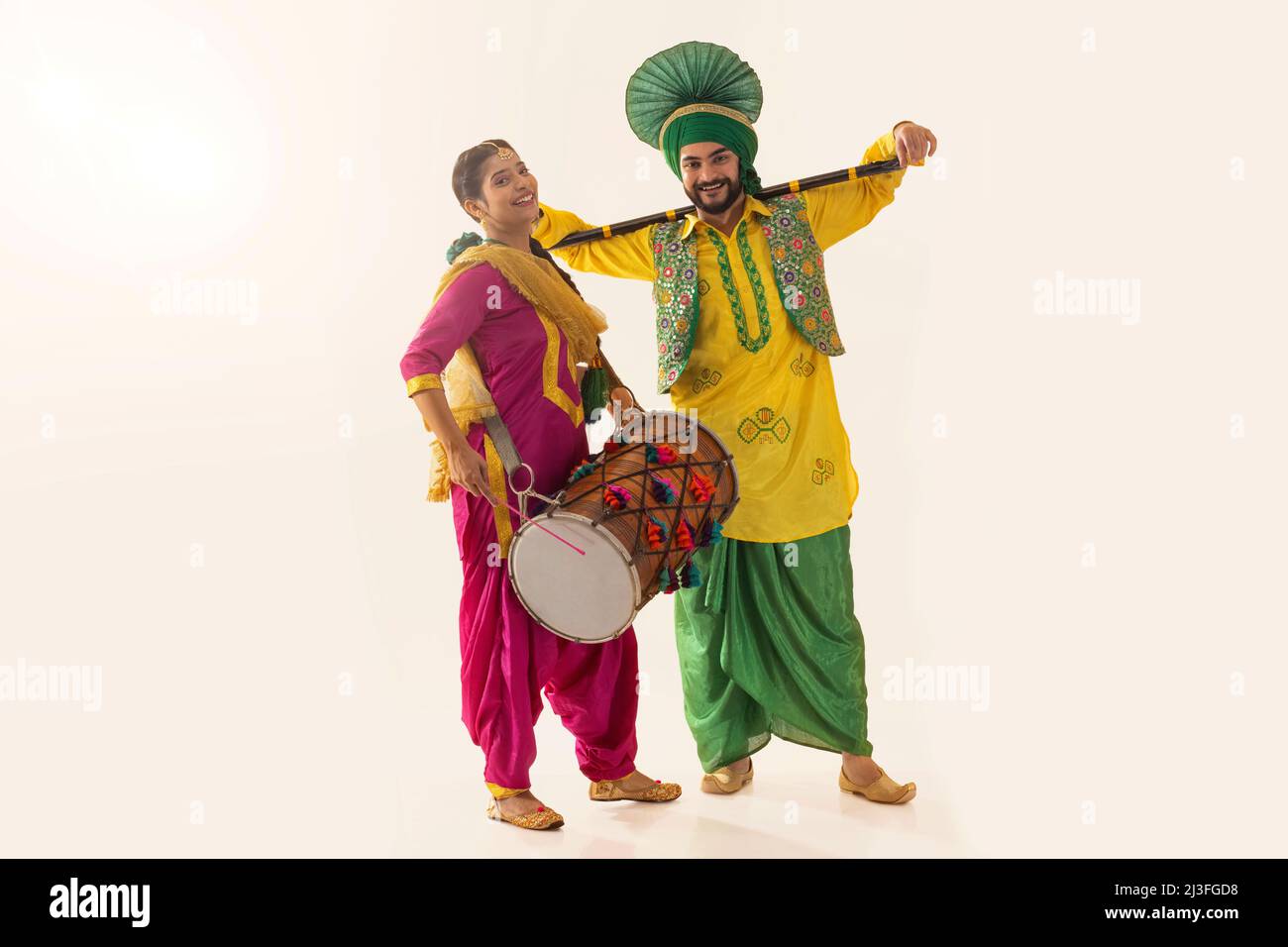 Sikh couple performing bhangra with drum and khunda during Baisakhi ...