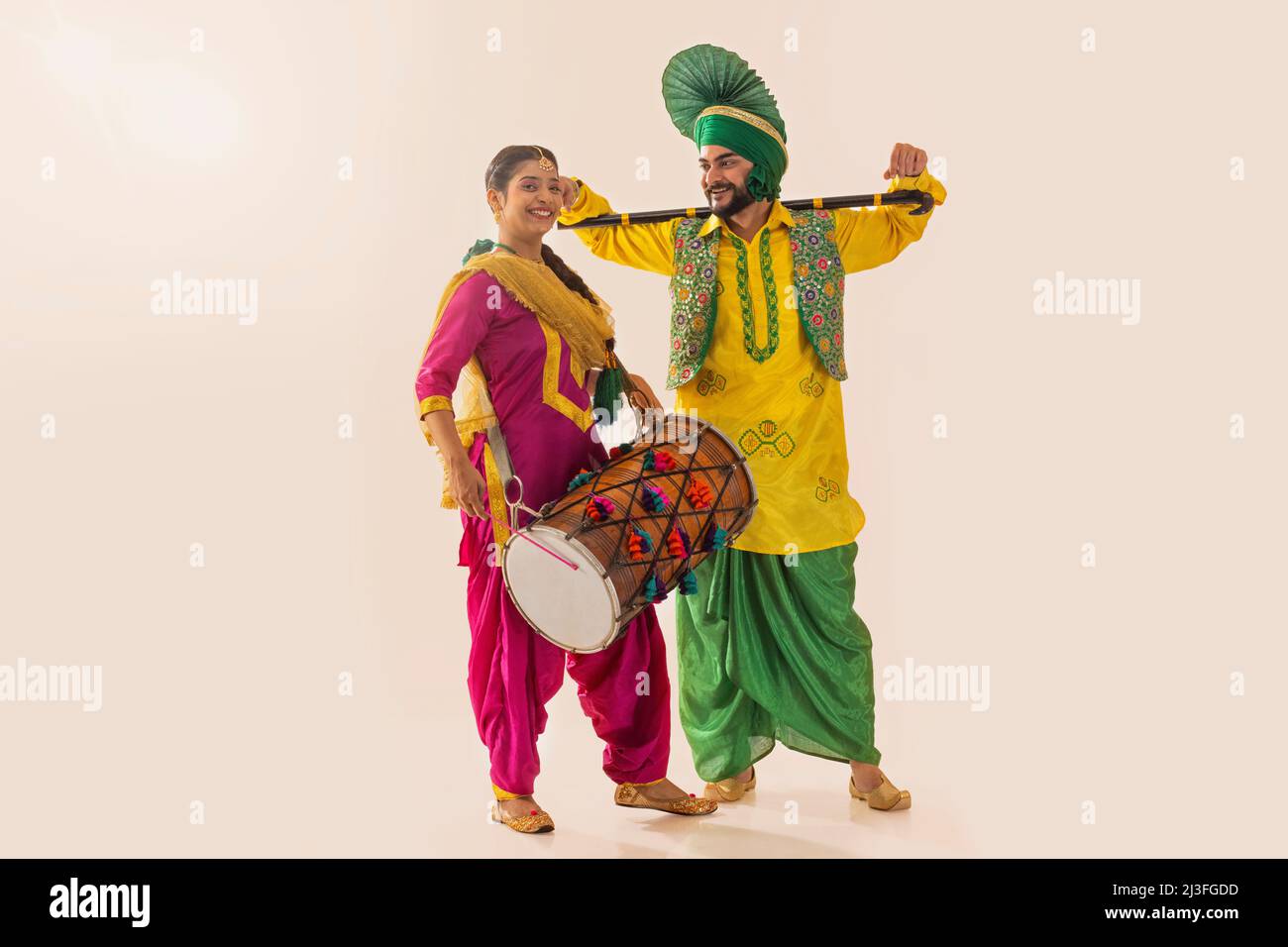 Sikh couple performing bhangra with drum and khunda during Baisakhi ...