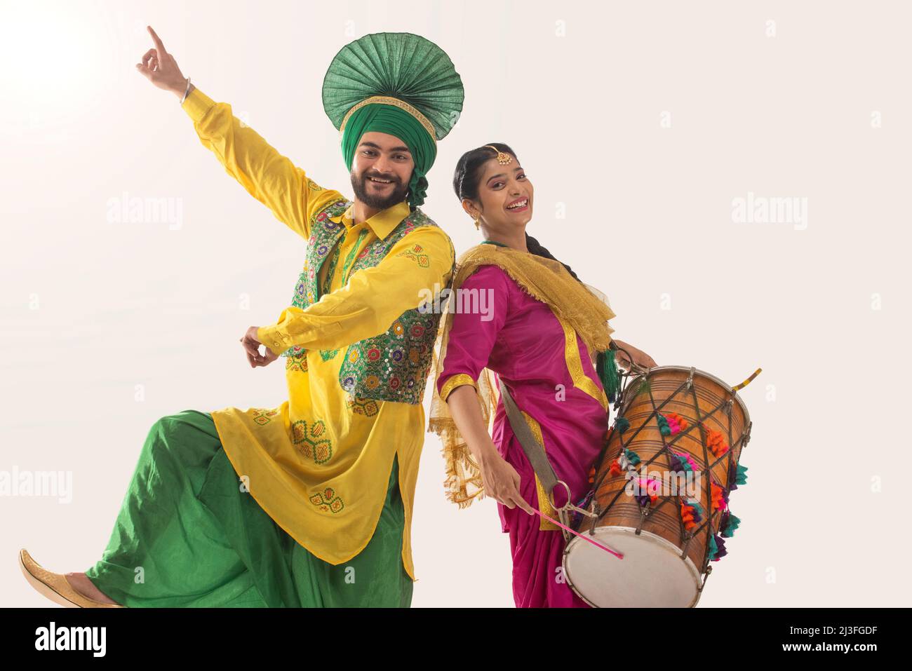 Sikh couple performing bhangra and playing drum during Baisakhi ...